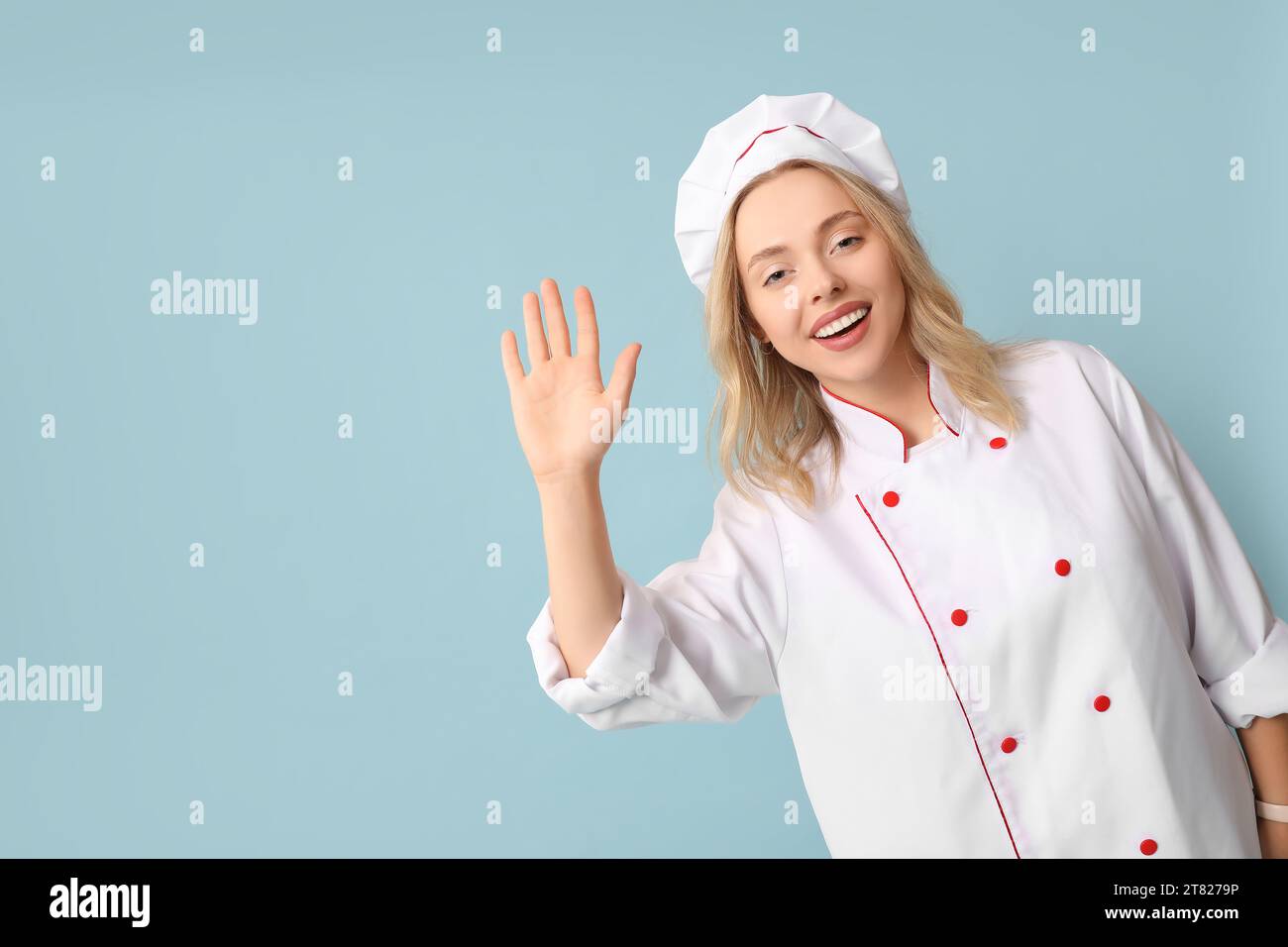Beautiful young female chef waving hand on blue background Stock Photo ...