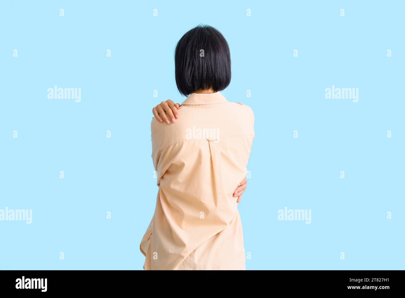 Young woman hugging herself on blue background, back view Stock Photo ...