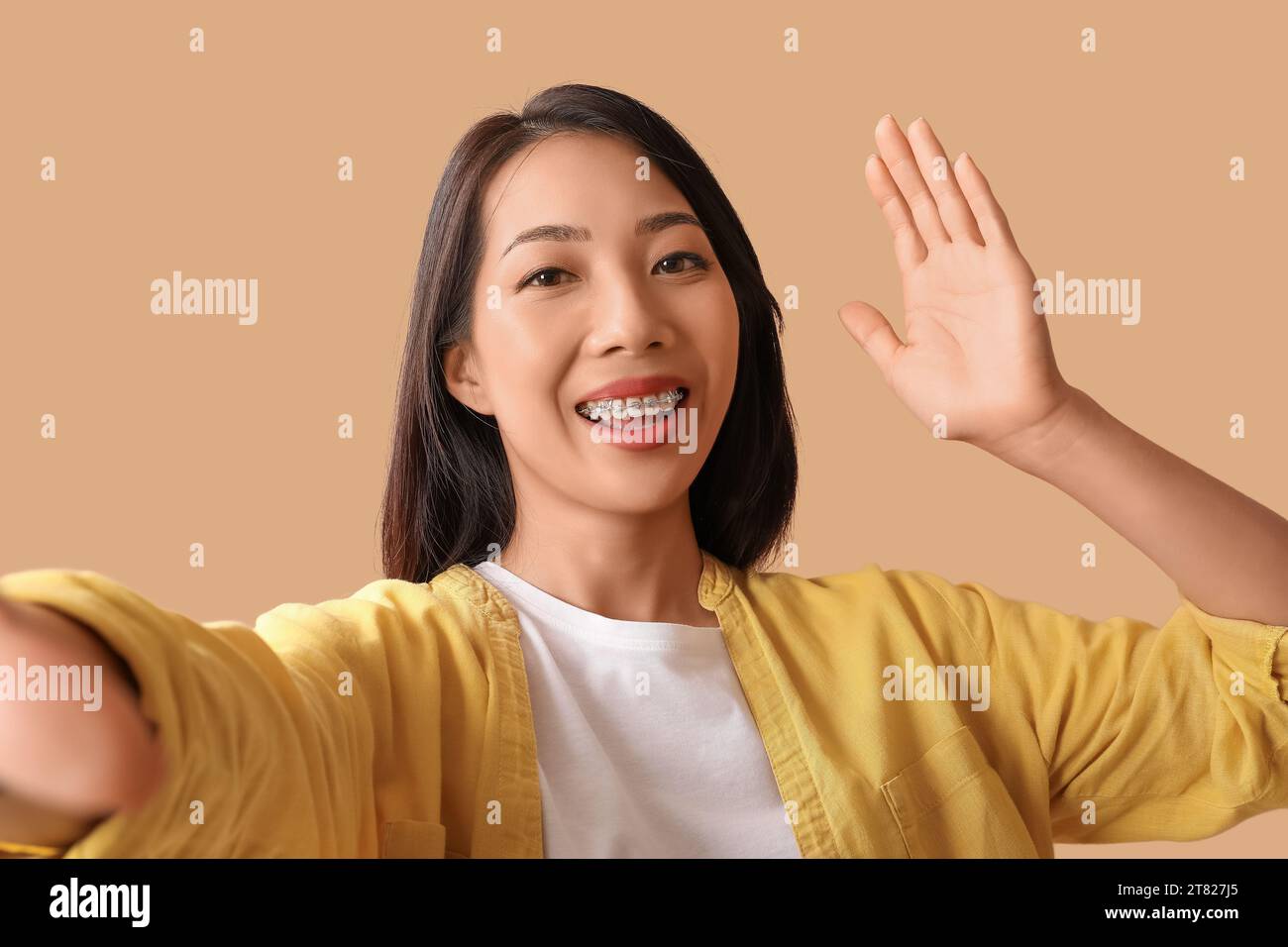 Beautiful young Asian woman waving hand on beige background Stock Photo ...