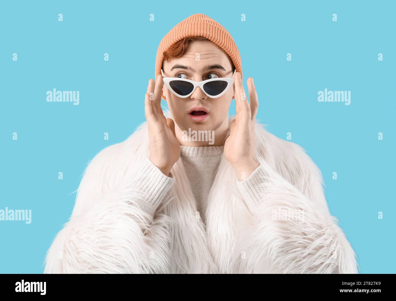 Stylish young man in fur coat on blue background Stock Photo - Alamy