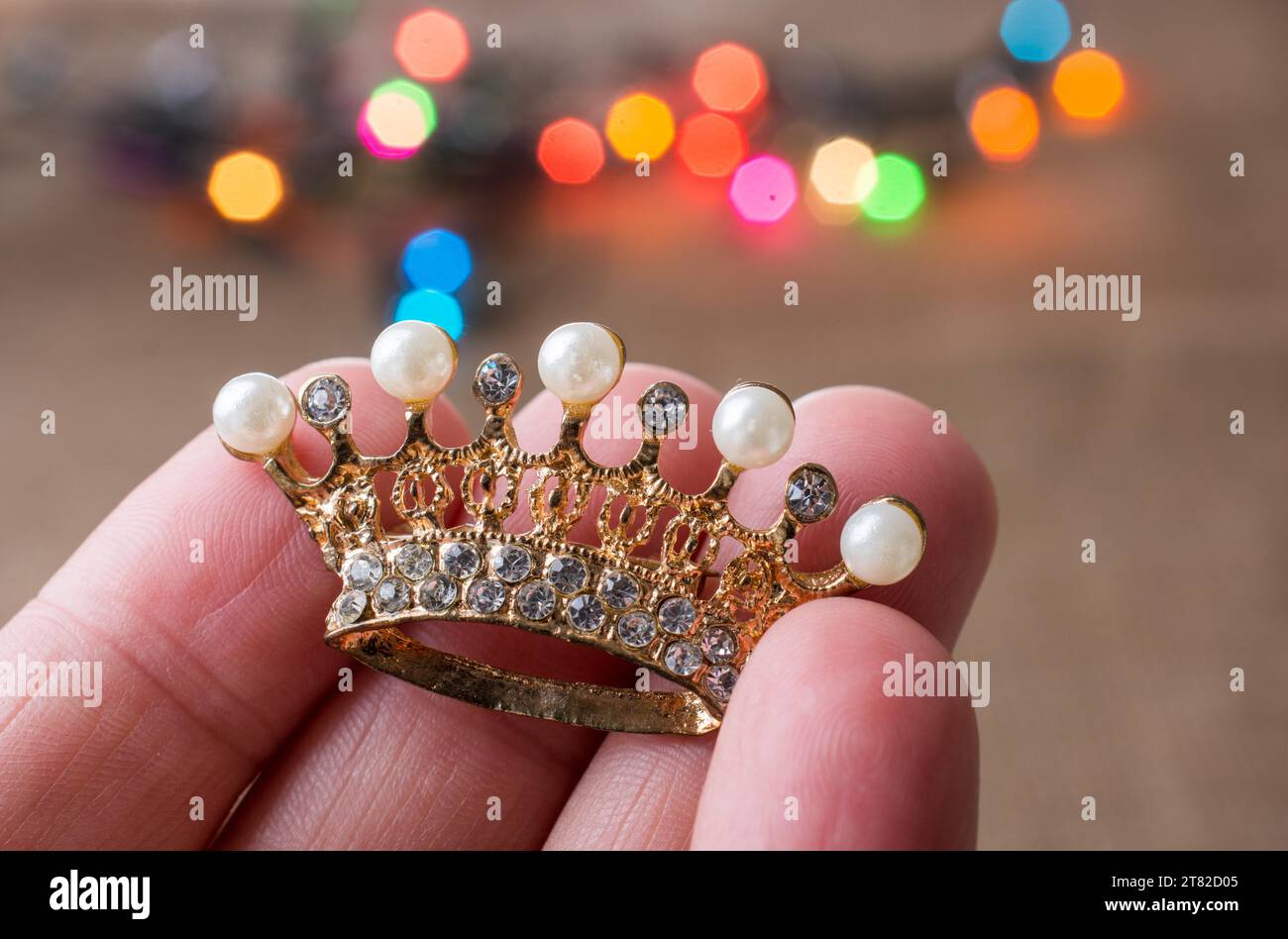 Little crown in hand with colorful lights behind Stock Photo - Alamy