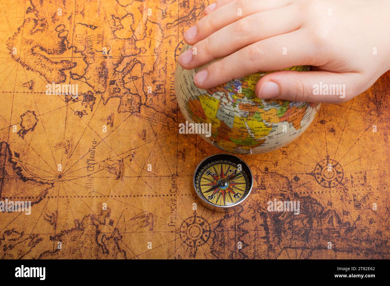 Compass on map beside a globe under hand Stock Photo - Alamy