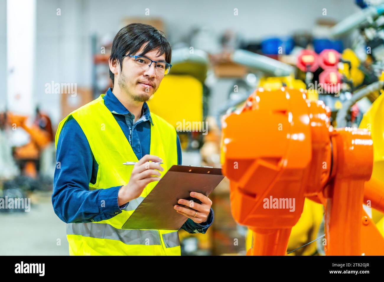 Young japanese engineer on duty controlling an industrial production ...