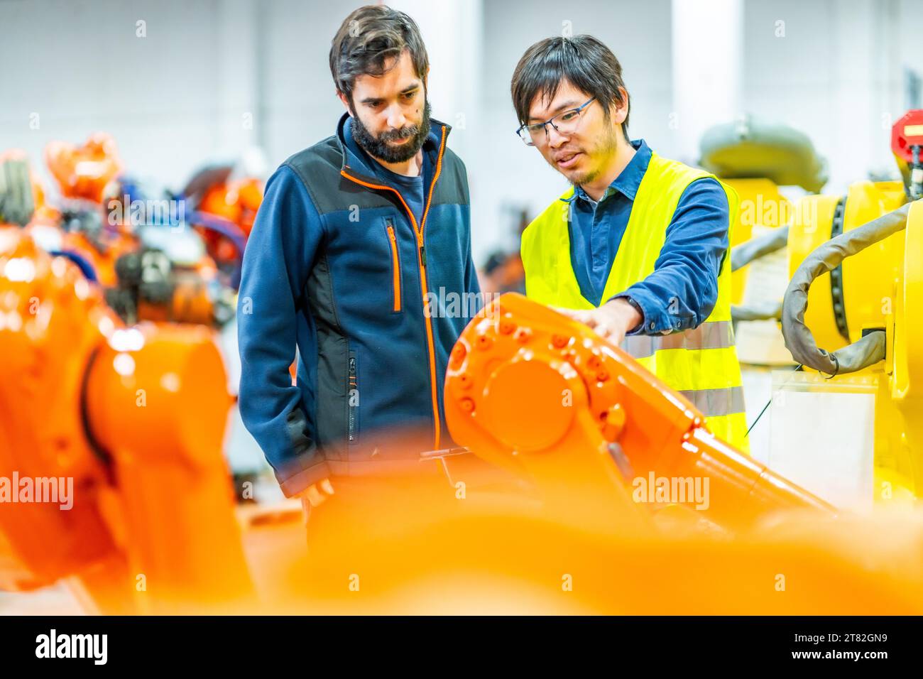 International team of engineers controlling assembly line of a robotics ...