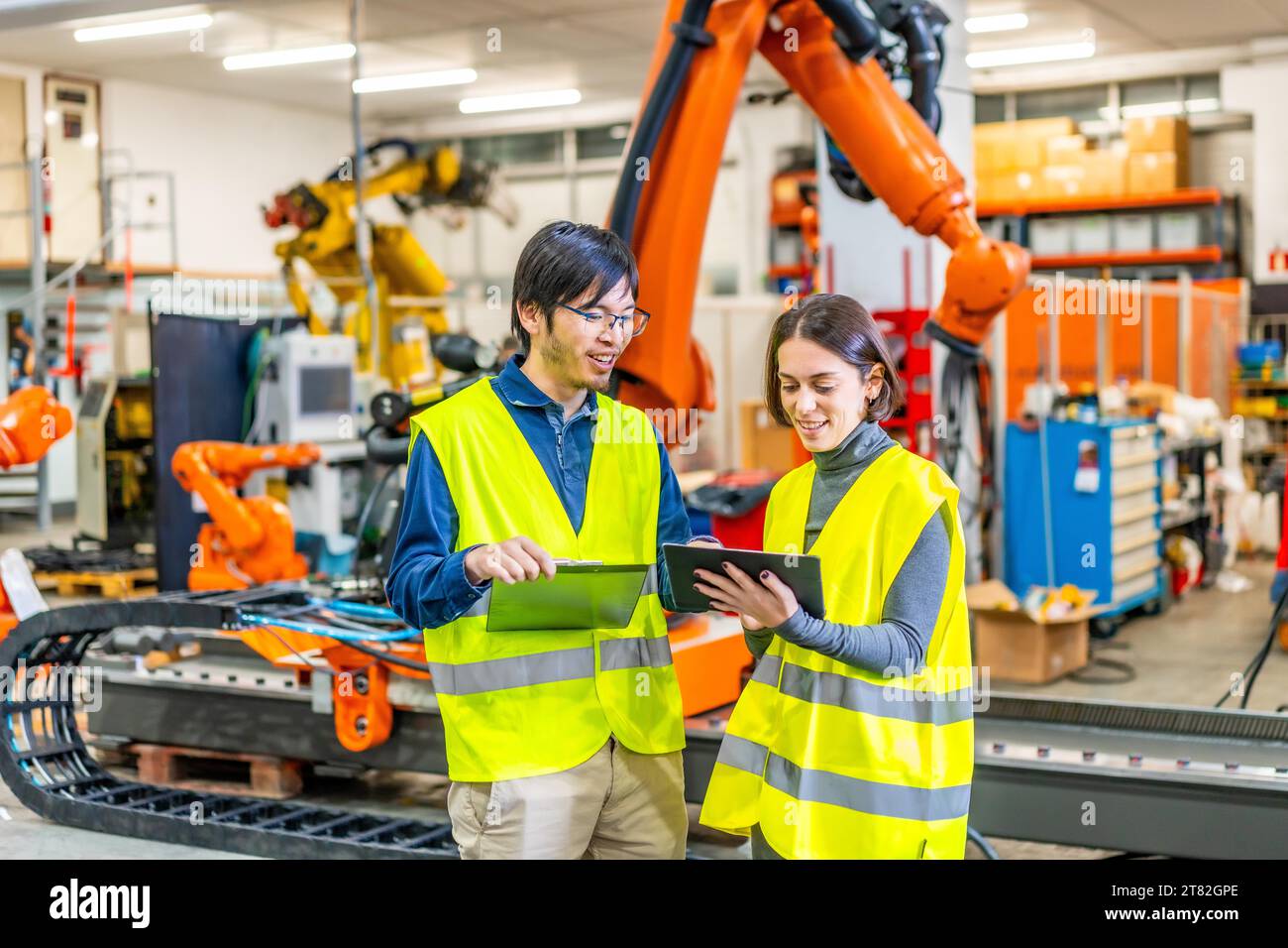 Engineers using digital tablet to control the production of a robotic arm factory Stock Photo ...