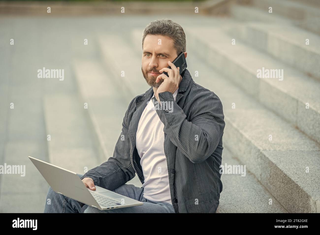 freelancing man with phone and laptop sitting outside. photo of ...