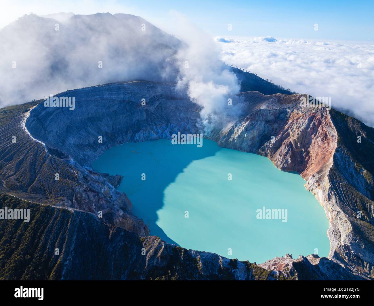 Aerial view of rock cliff at Kawah Ijen volcano with turquoise sulfur water lake at sunrise ...
