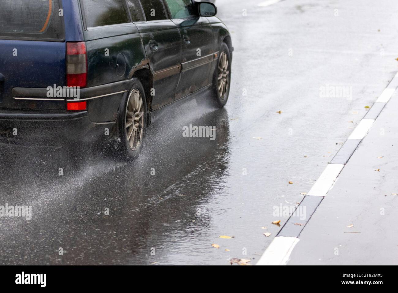 rain water splashing flows from wheels of old blue car that moving fast ...