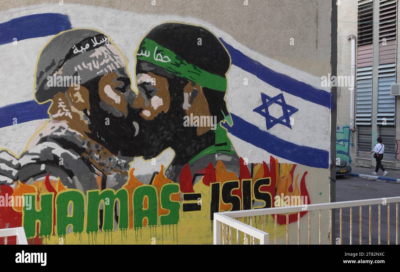 A woman passes by a painted graffiti depicting Hamas and Isis militants ...