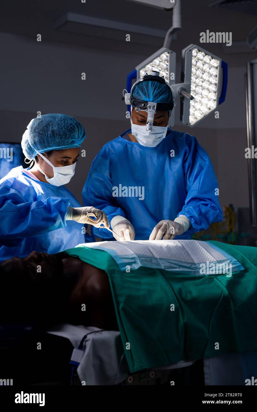 Diverse female doctors with face masks doing surgery in hospital ...