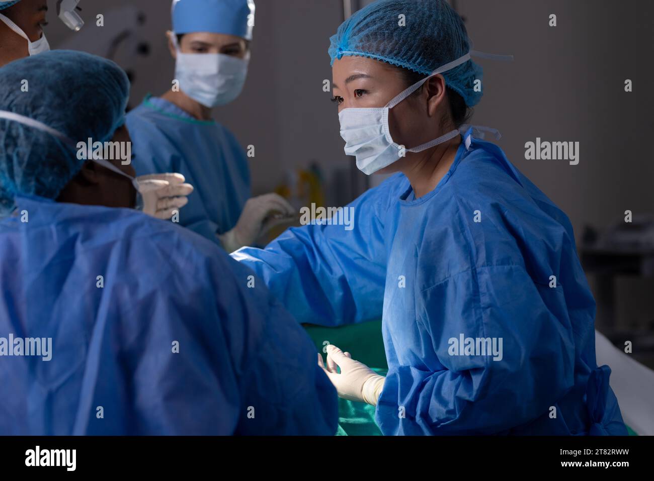 Diverse female doctors with face masks doing surgery in hospital ...