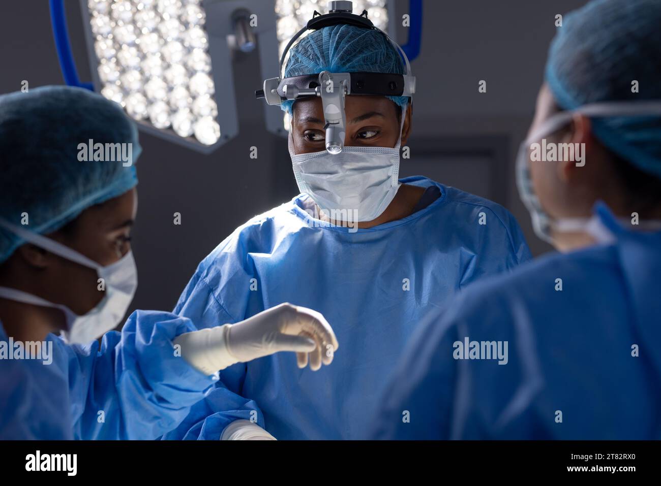 Diverse female doctors with face masks doing surgery in hospital ...