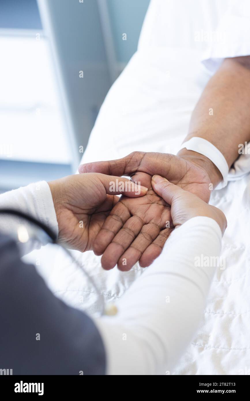Hands of diverse female doctor holding hand of senior female patient in ...