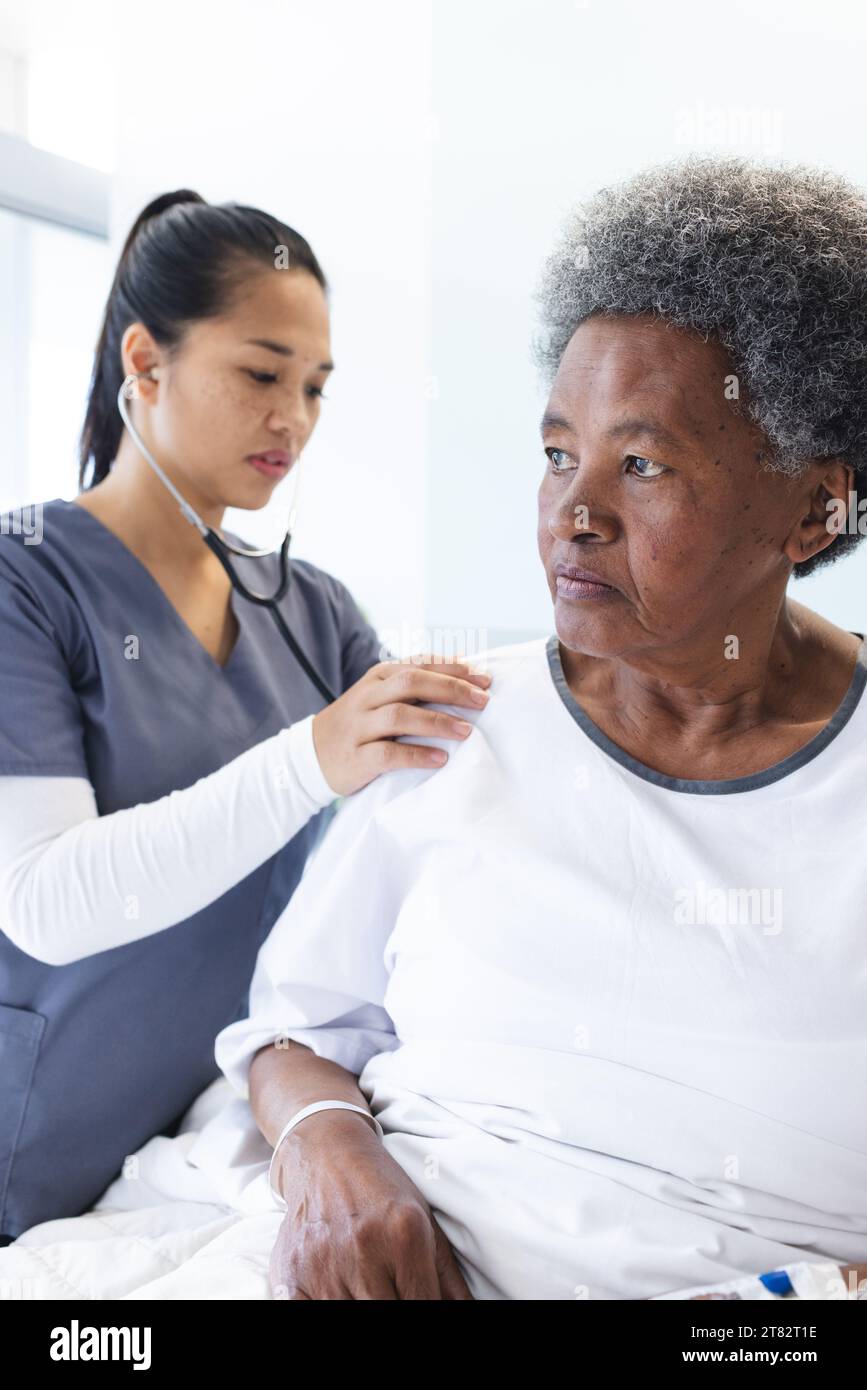 Diverse female doctor testing senior female patient using stethoscope ...