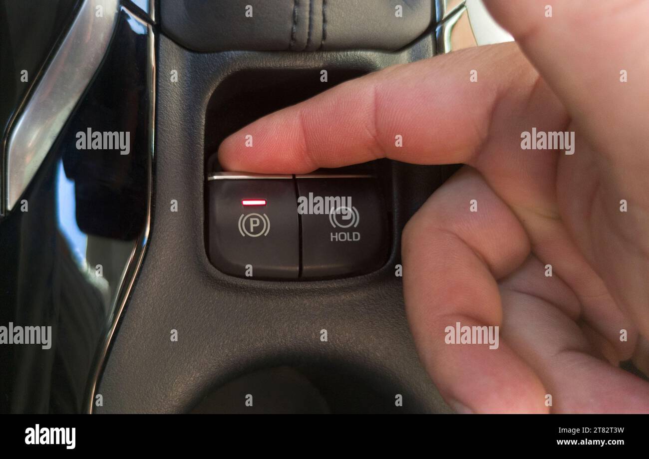 Driver activating the electric parking brake of his car. Selective ...