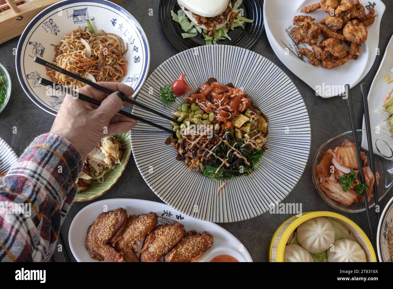 Hand holding chopsticks for eating at restaurant table Stock Photo - Alamy