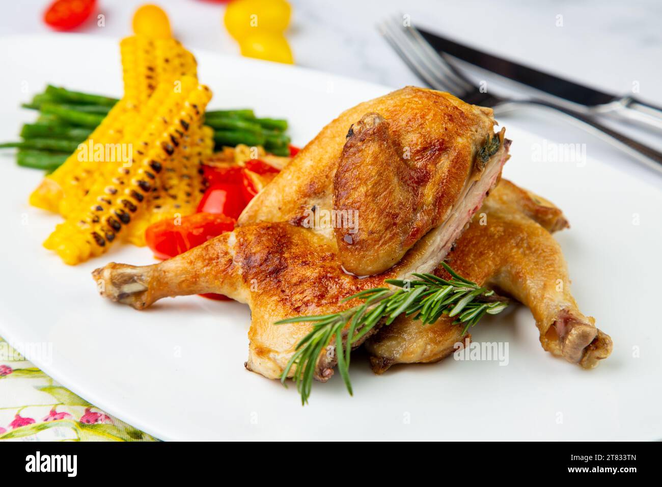 chicken thighs with corn, cherry tomatoes and herbs side view Stock ...