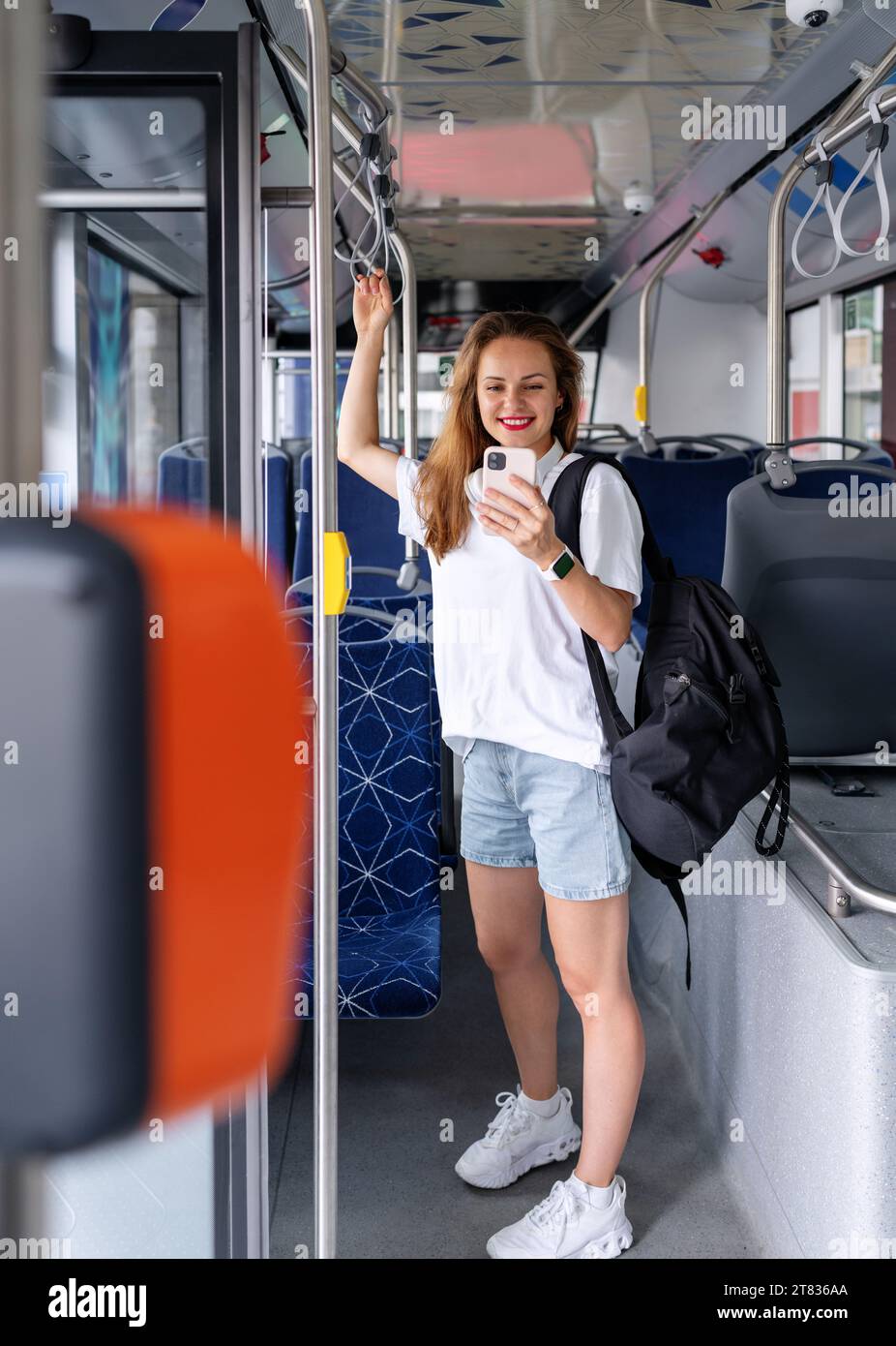Urban lifestyle, female passenger uses her mobile phone while standing ...