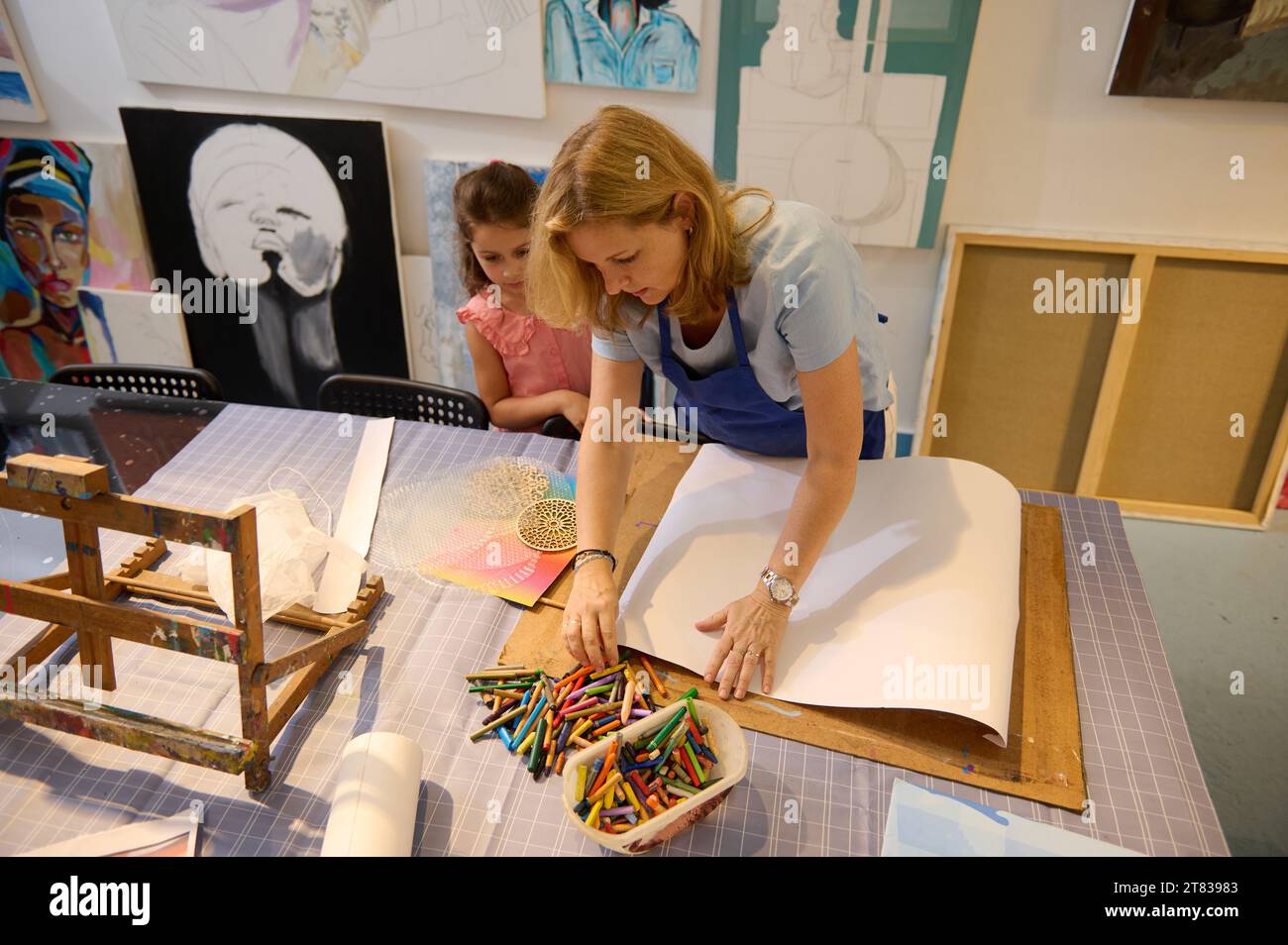 Beautiful blonde female painter artist teaching paint art to a little ...