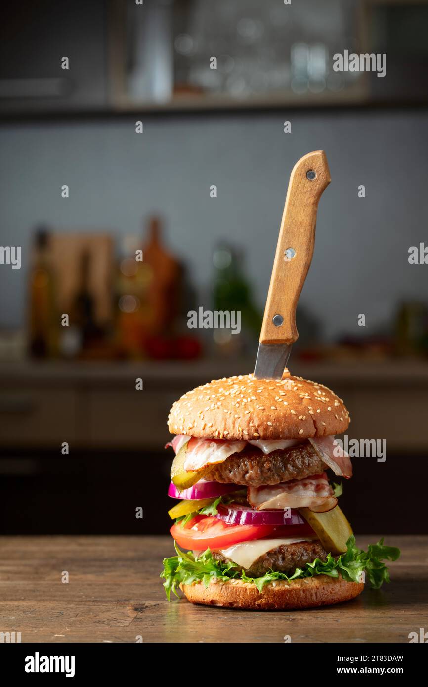 Fresh burger with knife on a kitchen table. Burger with tomato, onion ...