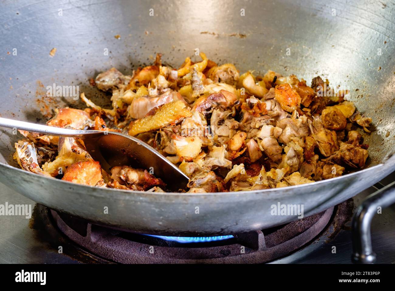 Stir frying chicken meat and garlic in steel wok with a spatula ...