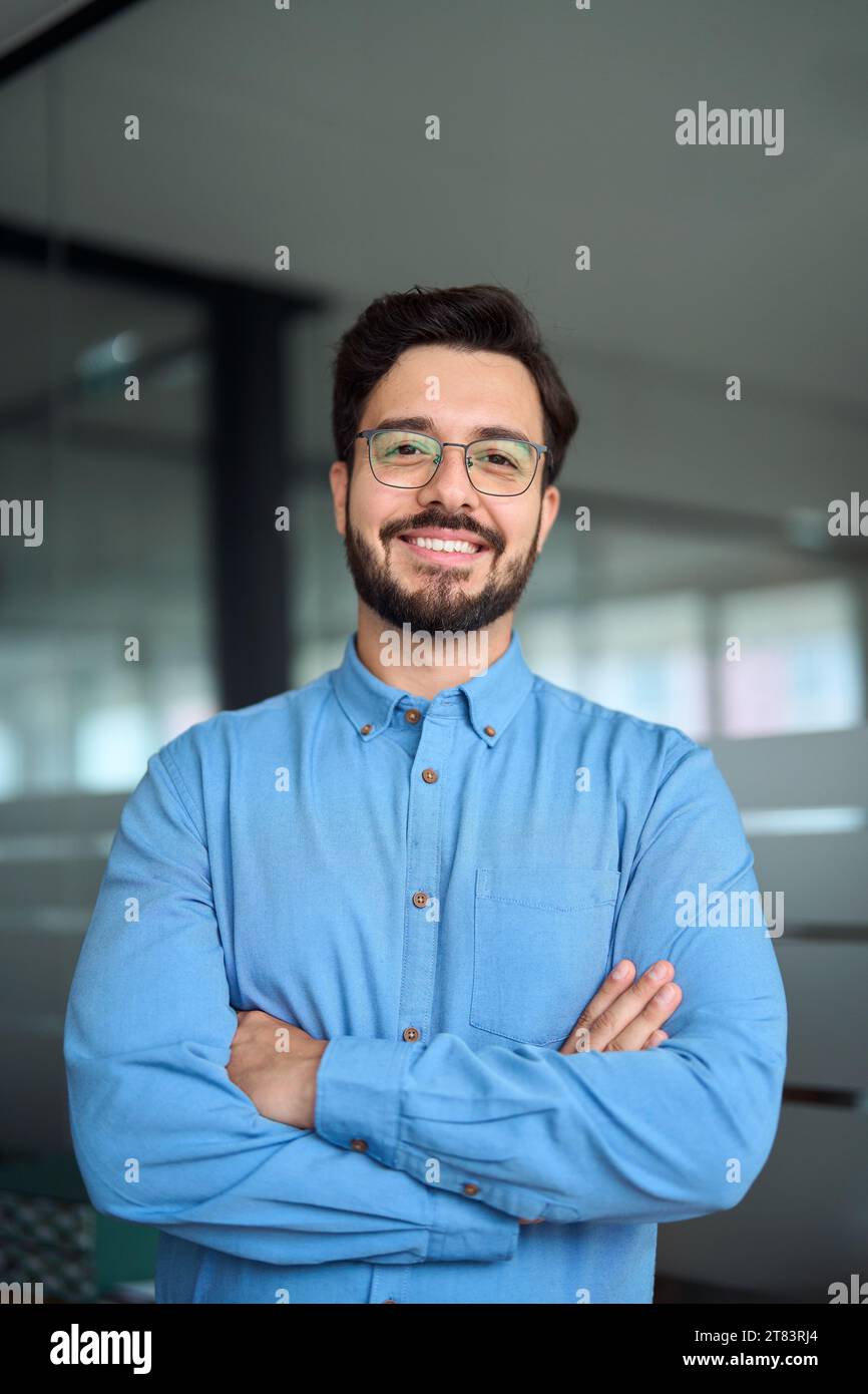 Happy young latin business man leader standing in office, vertical ...