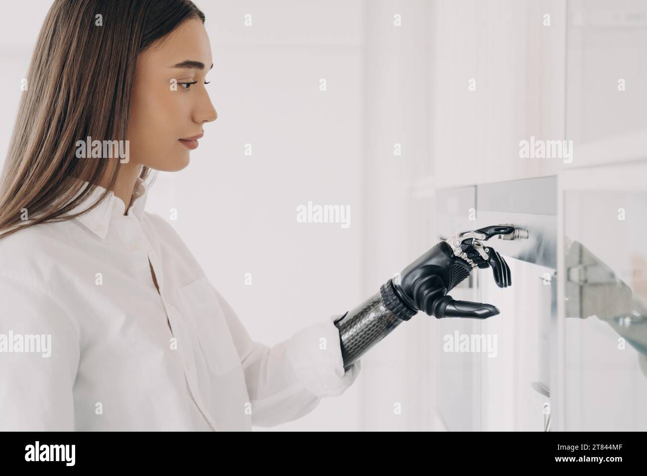 Focused woman using a sophisticated bionic hand to interact with a ...