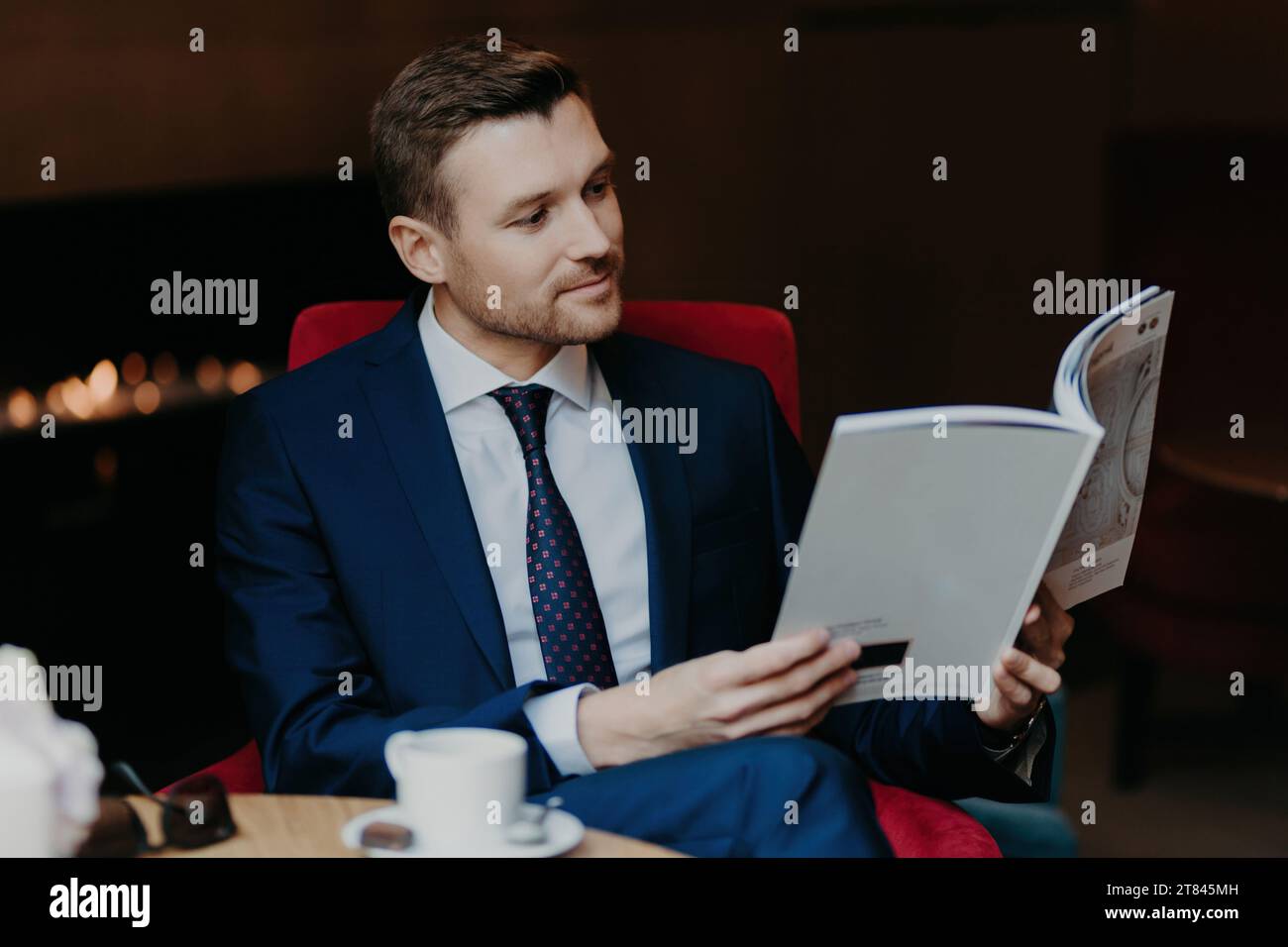 Serene executive reading a magazine, enjoying a coffee break in an ...