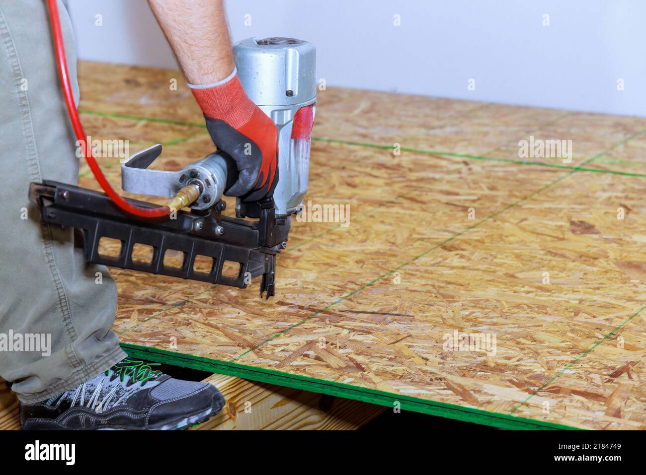 New home with installation wooden plywood to floor using air nail gun ...