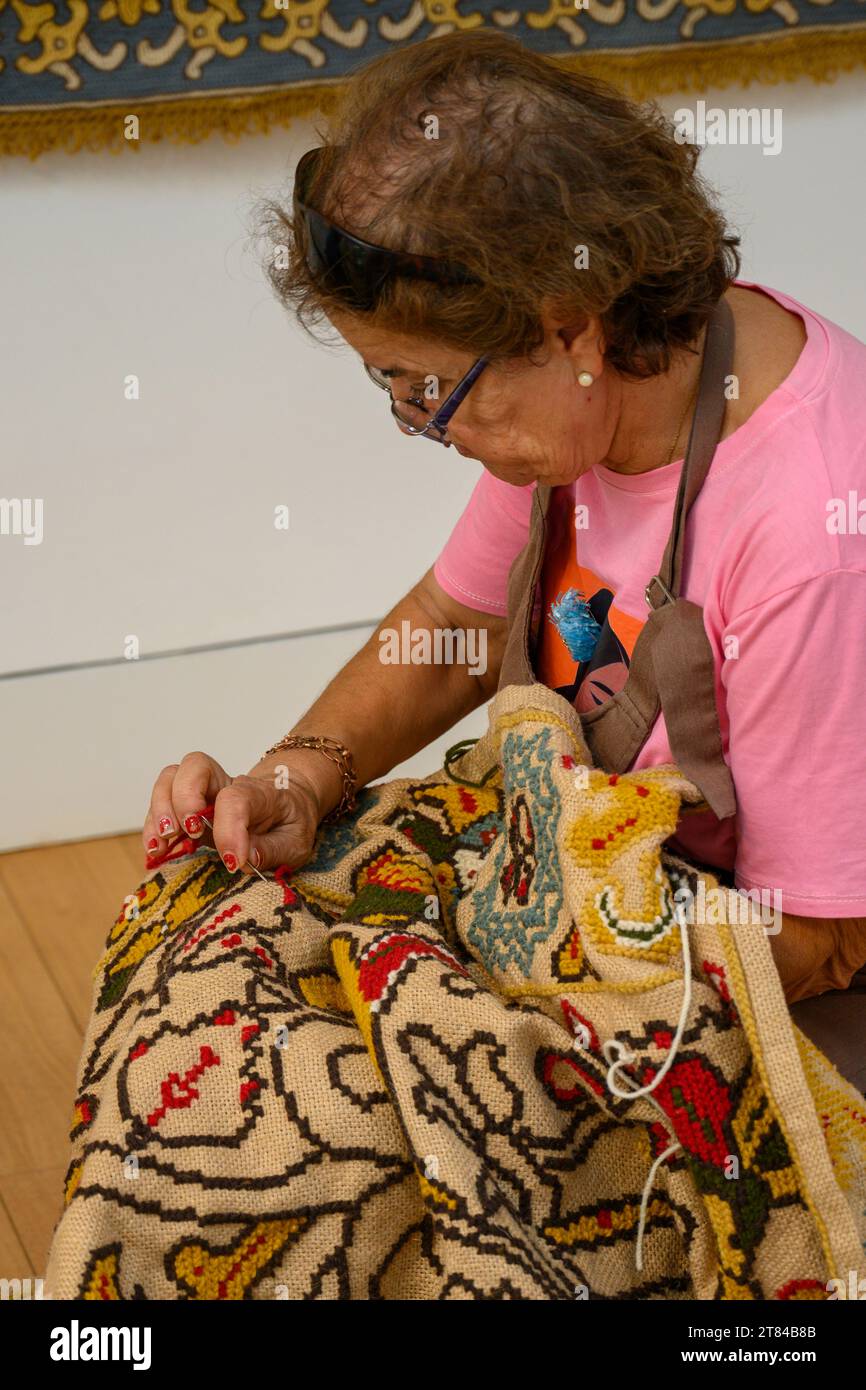 Woman is embroidering tapestry in the traditional way and design at the ...