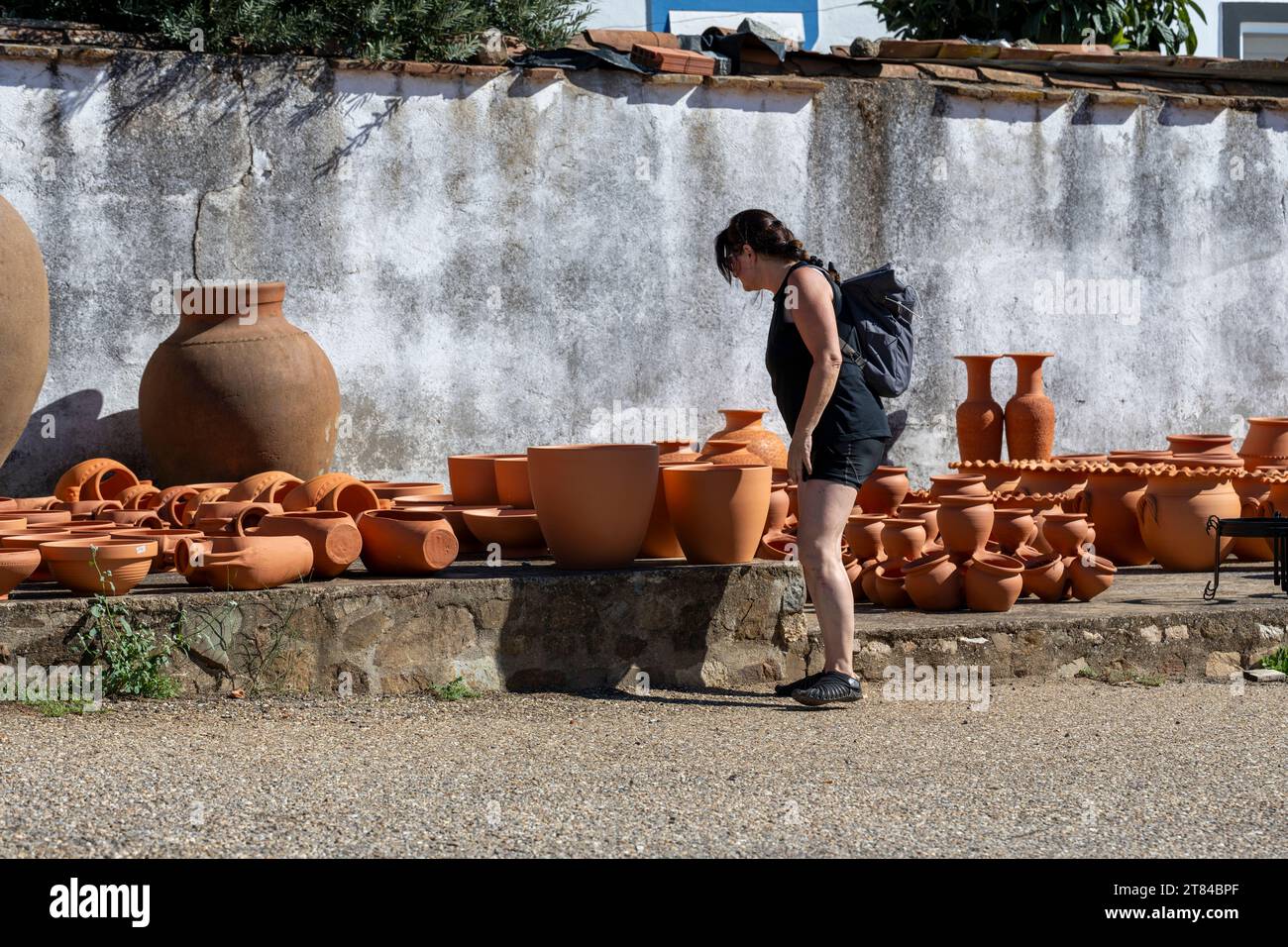 Tourist inspects the handmade earthenware pots at pottery factory in ...
