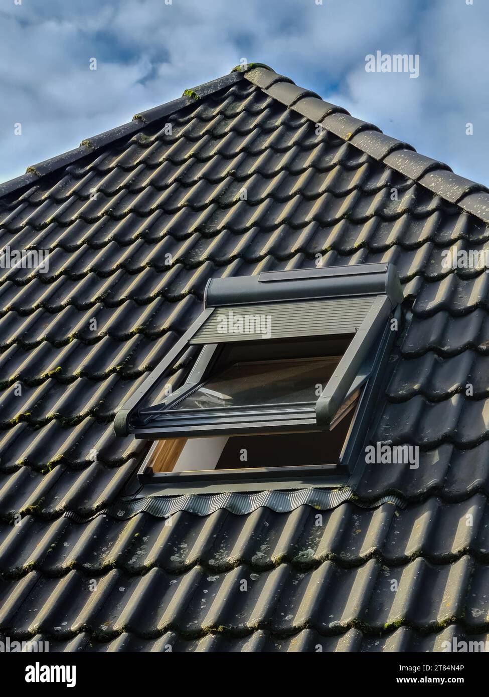 Open roof window in velux style with black roof tiles Stock Photo - Alamy