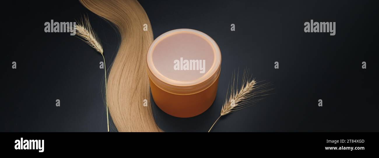 Blond long hair with cream jar and sprigs of ripe wheat. Healthy hair ...