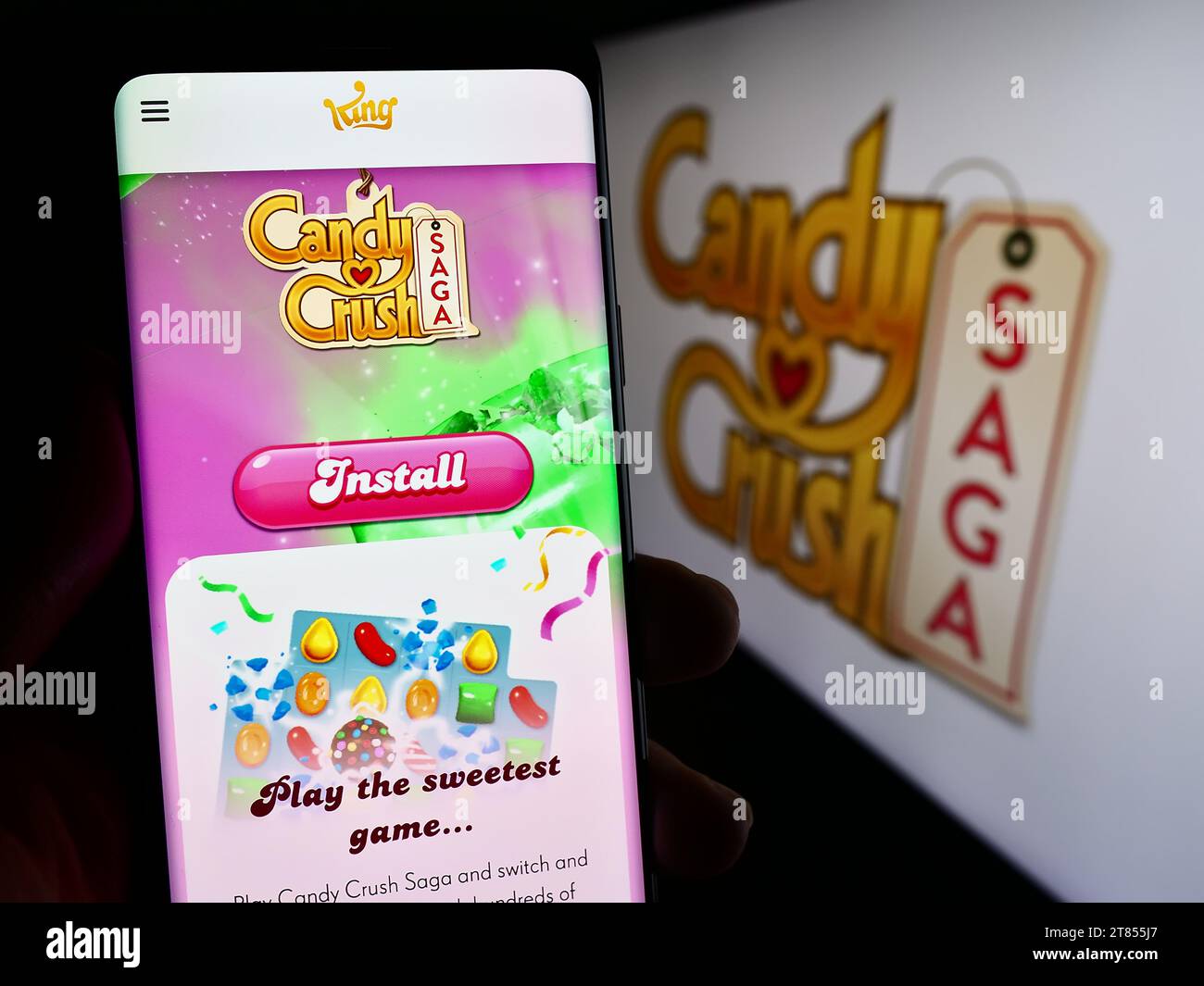Person holding mobile phone with web page of tile-matching video game ...
