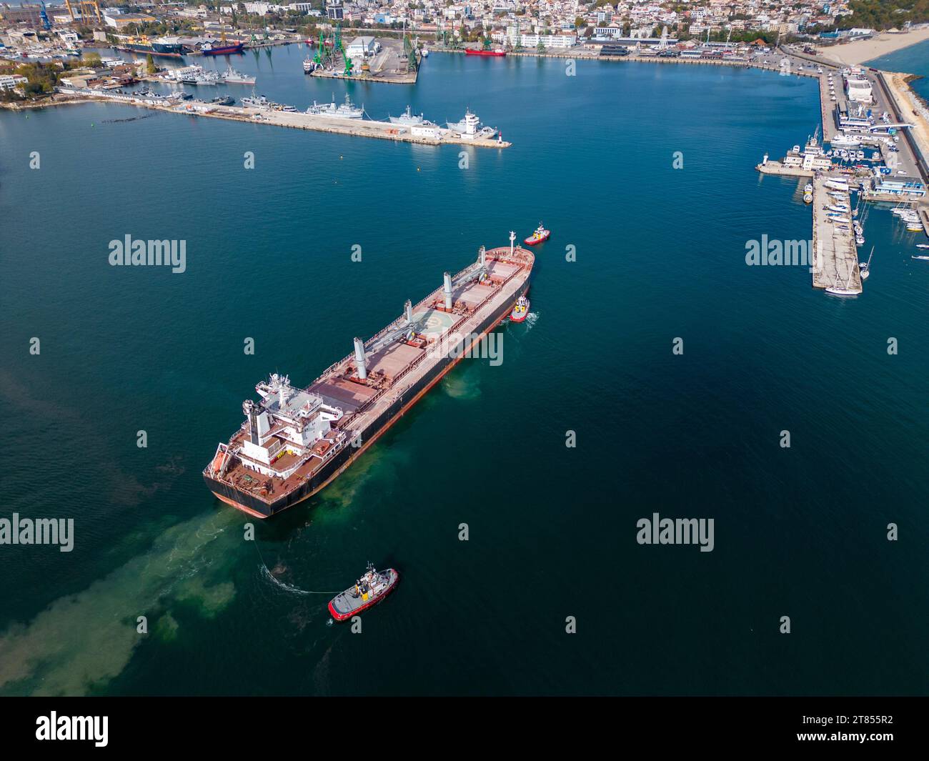 A massive cargo ship bulk carrier leaves the seaport, accompanied by ...