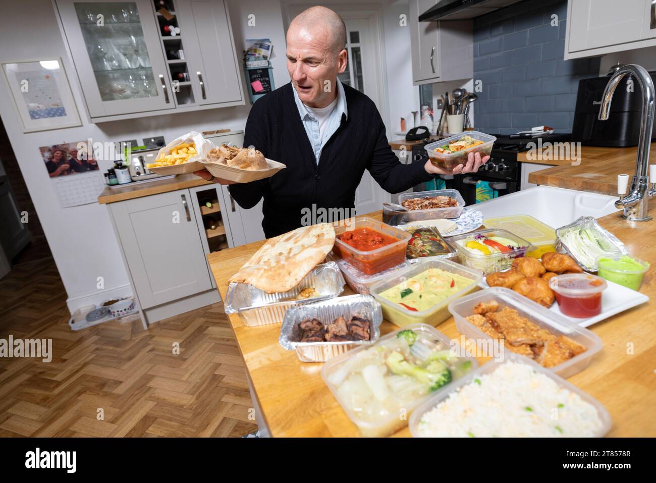 Man at home with section of take-away food on his kitchen work top ...