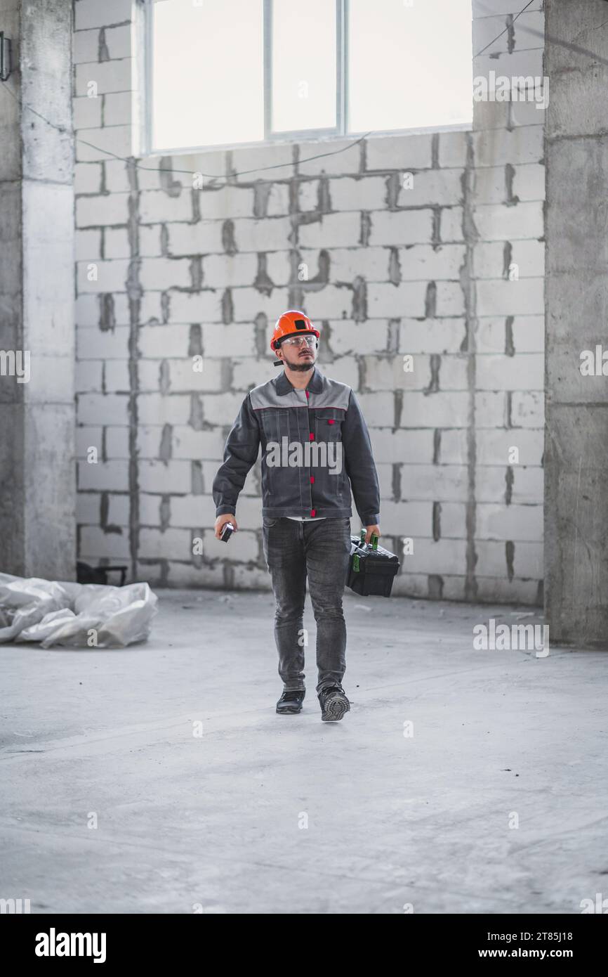 Workman ready for renovation work. Builder in uniform carrying toolbox ...