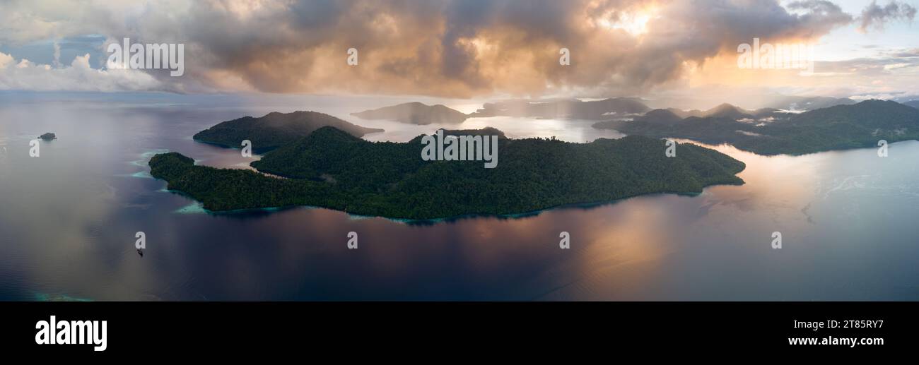 Tropical islands, surrounded by calm seas, are illuminated at sunrise ...
