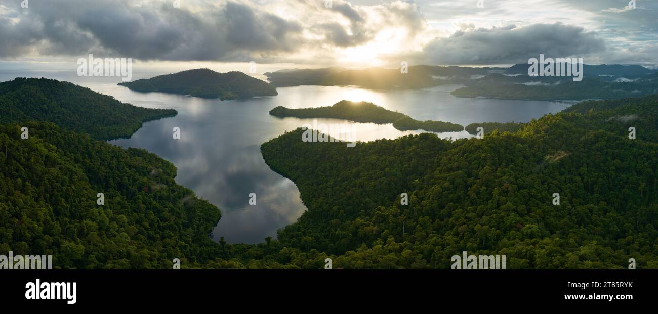 Tropical islands, surrounded by calm seas, are illuminated at sunrise ...