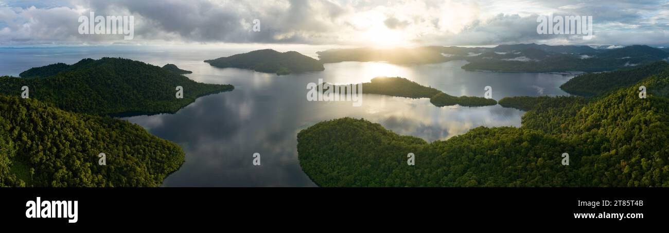 Tropical islands, surrounded by calm seas, are illuminated at sunrise ...