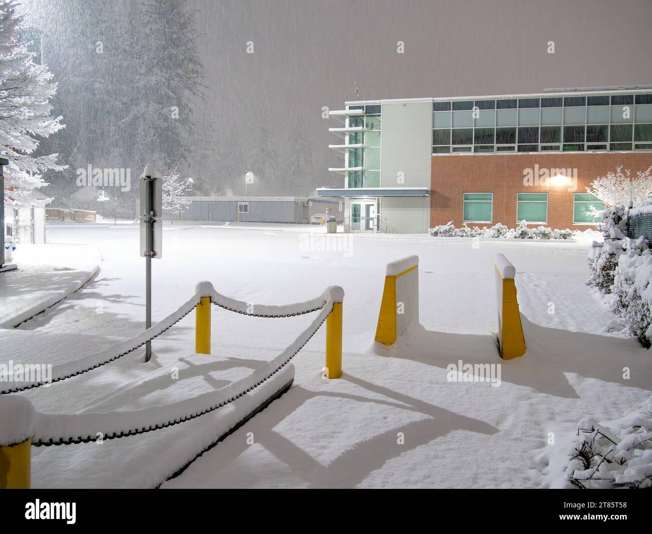 Office building with a parking lot covered in snow under the night ...