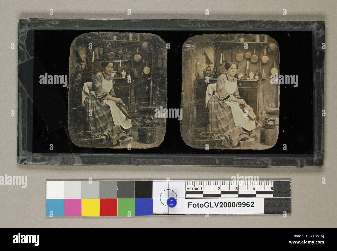 Anonym Young woman with a blasbalg on a coal cooker in a kitchen ...