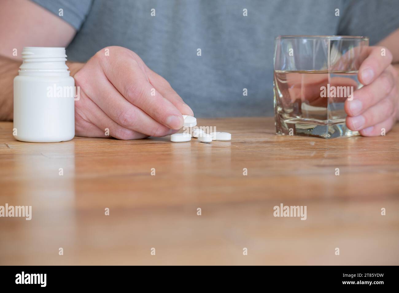 Person taking their medicine sitting at the kitchen table Stock Photo ...