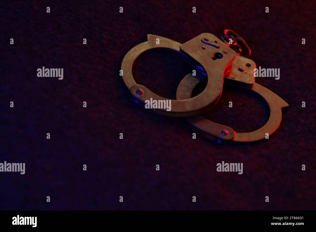 Closed handcuffs on the dark surface at night with police car lights ...