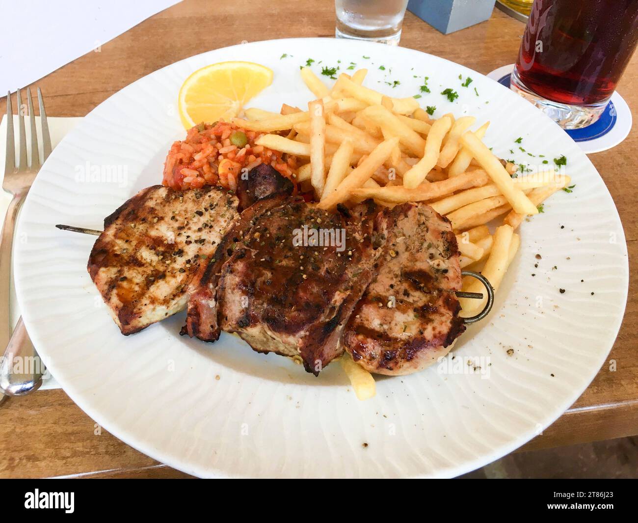Grillspieß mit Pute, Rind, Lamm und Schwein mit Pommes frites und Reis ...