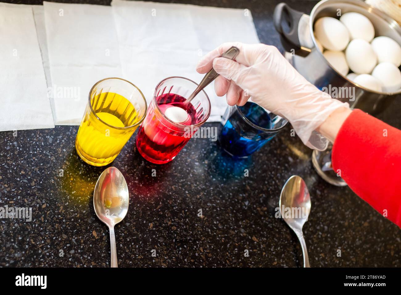 A woman dyes chicken eggs in multi-colored food dyes. Preparing for the ...