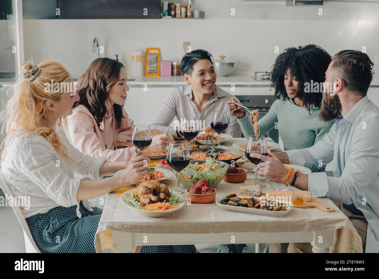 Group of multiethnic friends sitting at the table during lunch. Table ...