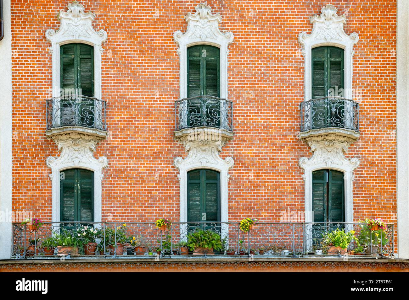 brick wall with six dark green balcony doors leading to narrow balcony ...