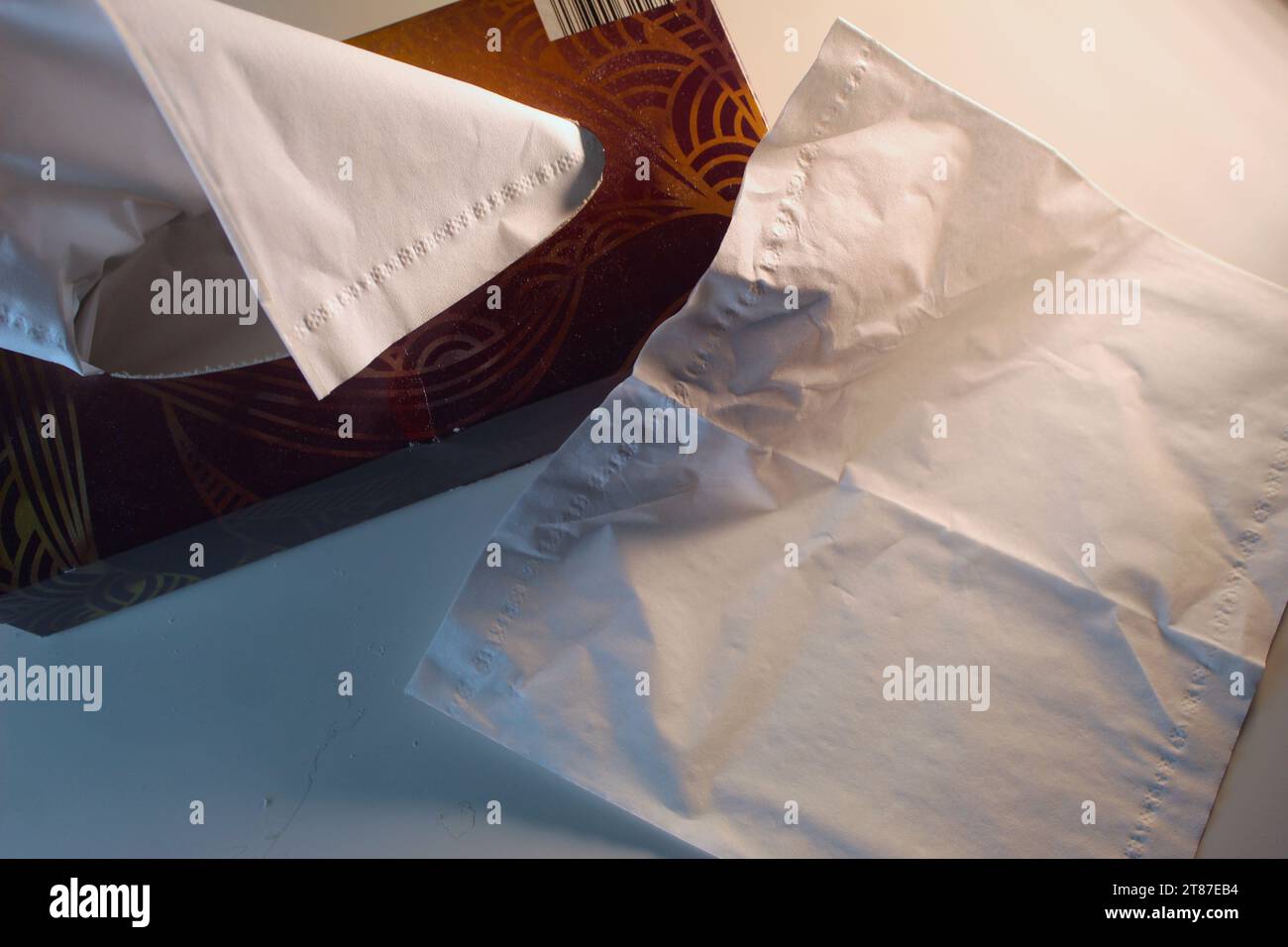 A photo of a rectangular tissue box for colds and flus on a white desk ...