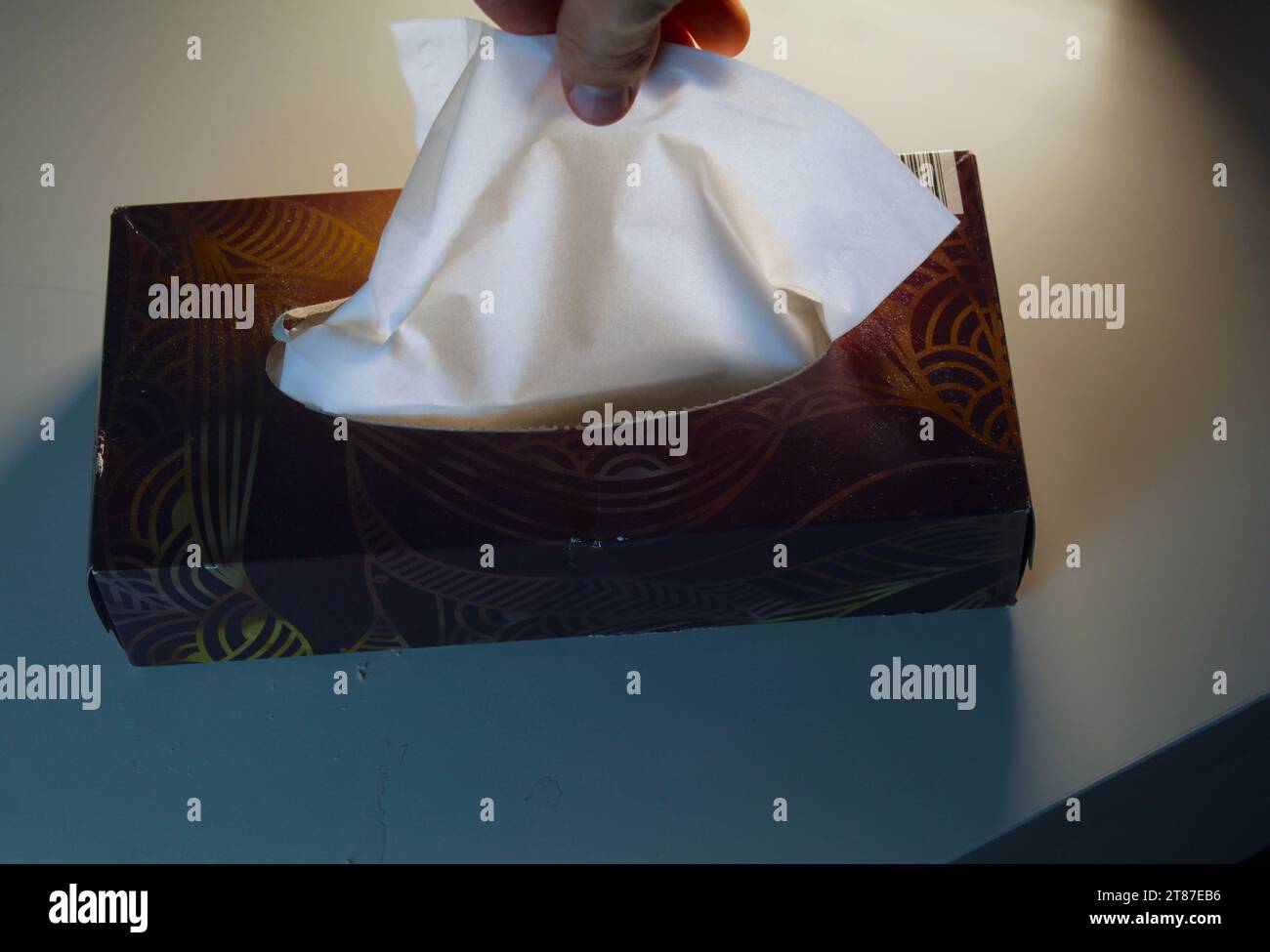 A photo of a rectangular tissue box for colds and flus on a white desk ...